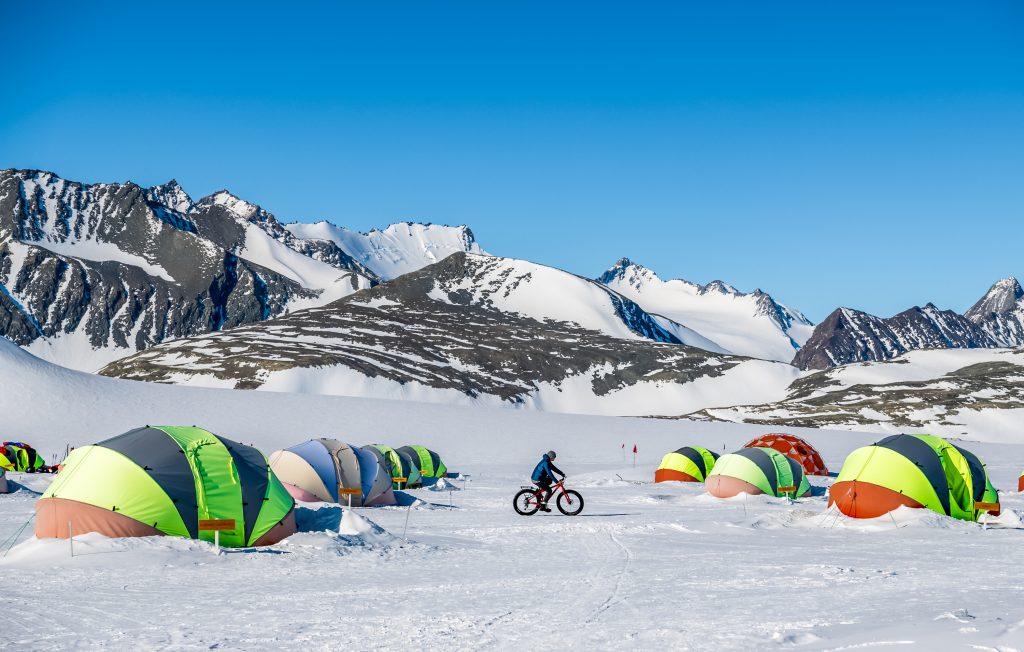 A guest rides a bike through the clam tents at Union Glacier Camp ...